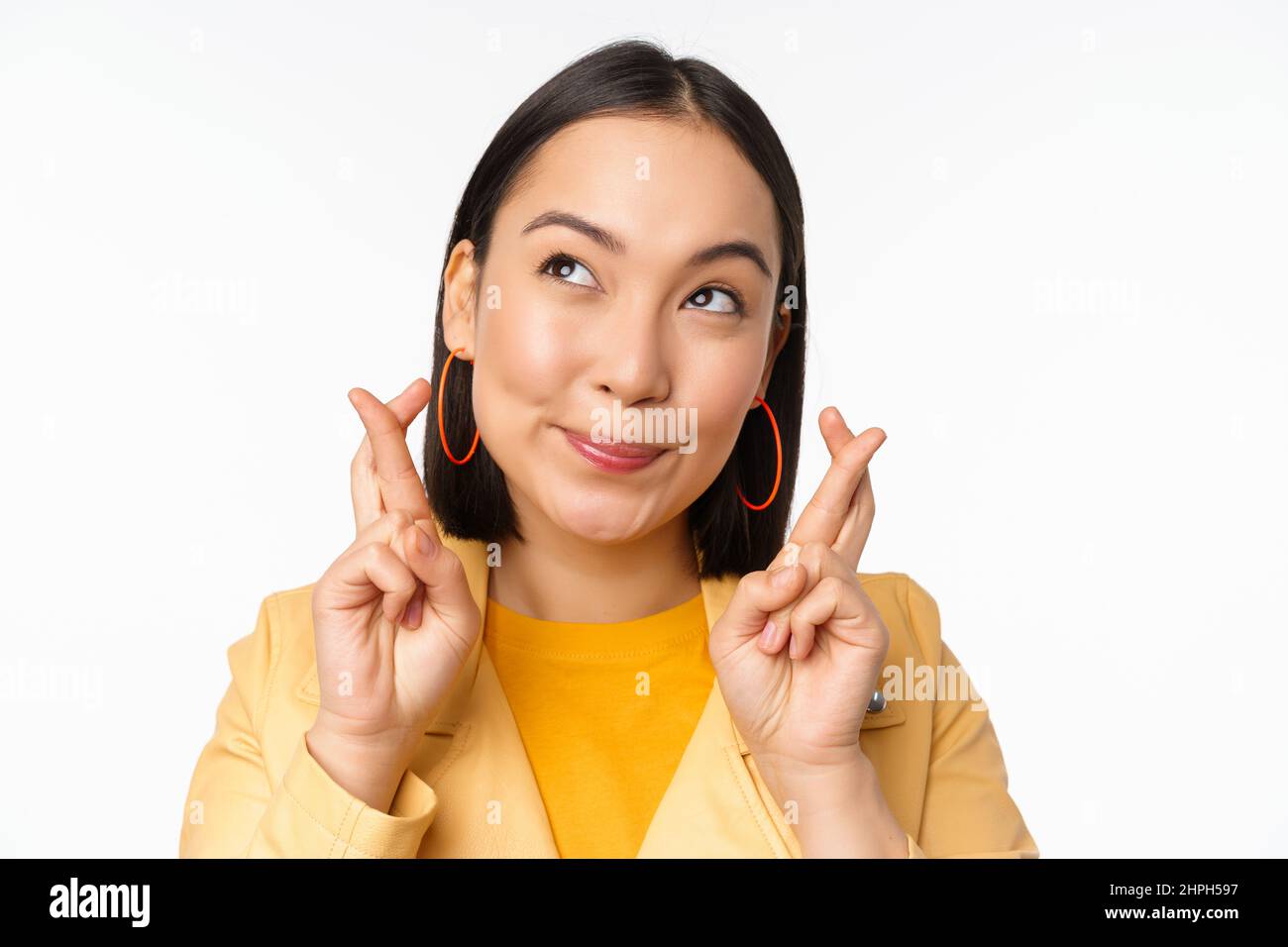 Close up portrait of hopeful asian girl wishing, cross fingers for good ...