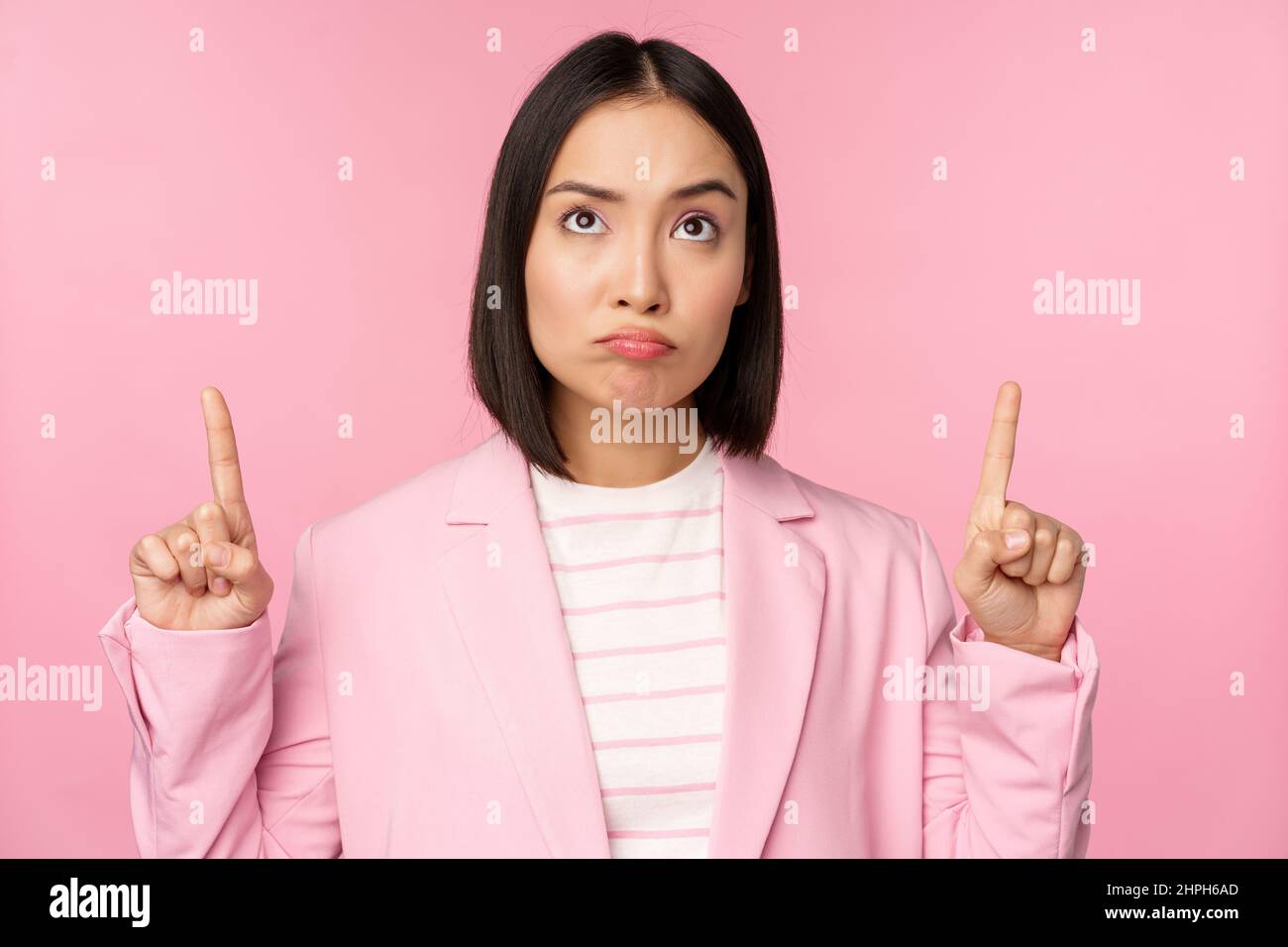 Upset asian corporate woman in office suit, pointing and looking up ...