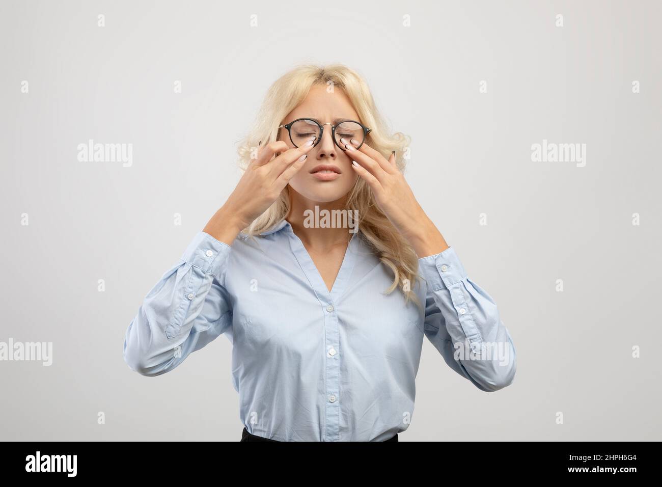 Tired female office worker touching eyes, wearing glasses and suffering ...