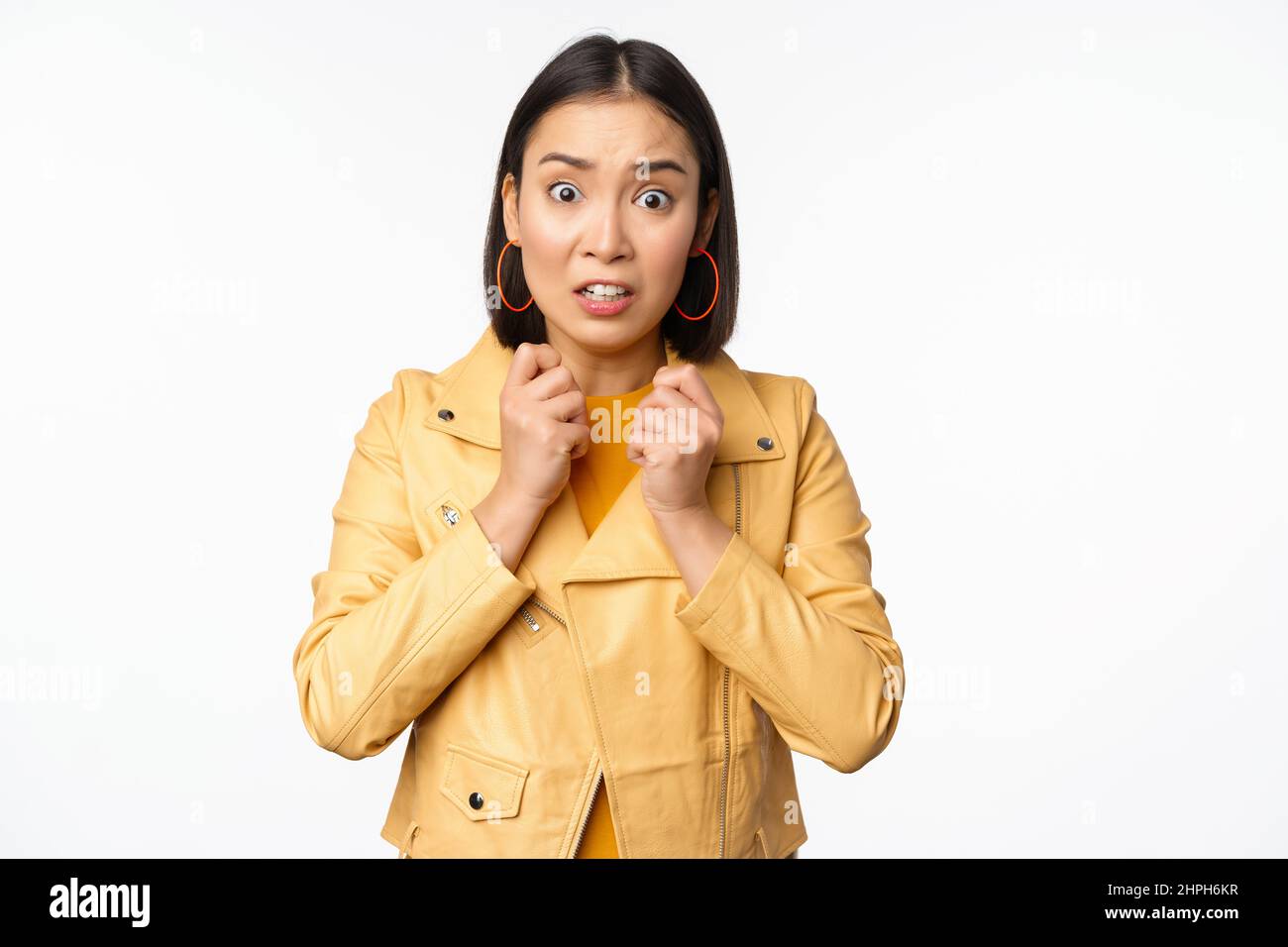 Image of scared asian woman looking insecure and worried at camera ...