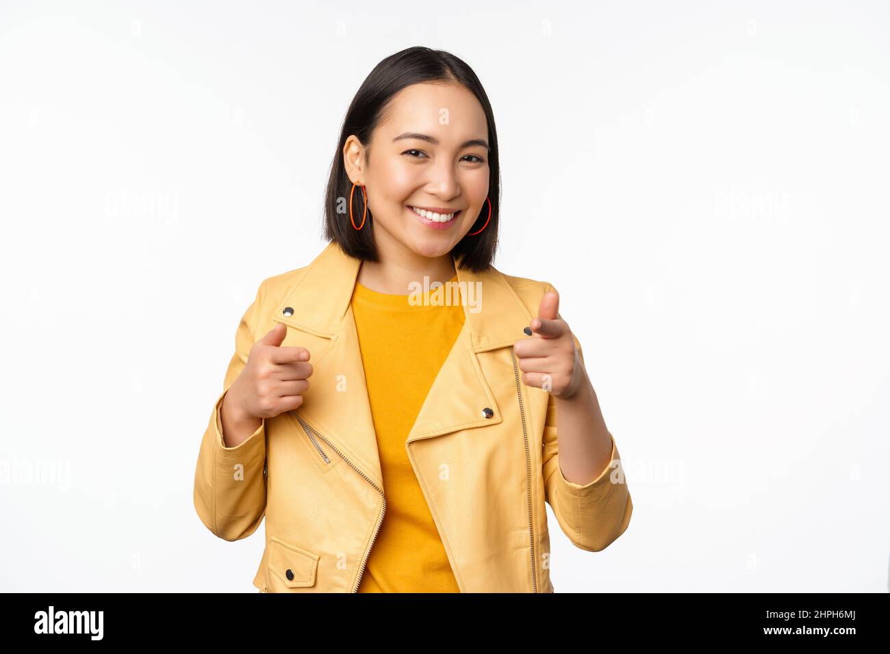 Hey you. Happy smiling asian woman pointing fingers at camera, choosing ...