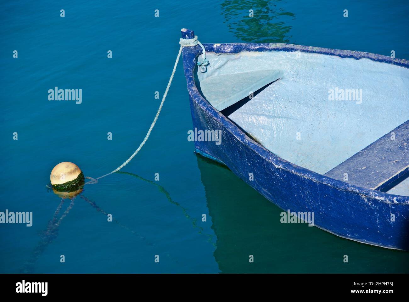 Small blue boat anchored at a floating buoy in the Mediterranean Sea ...