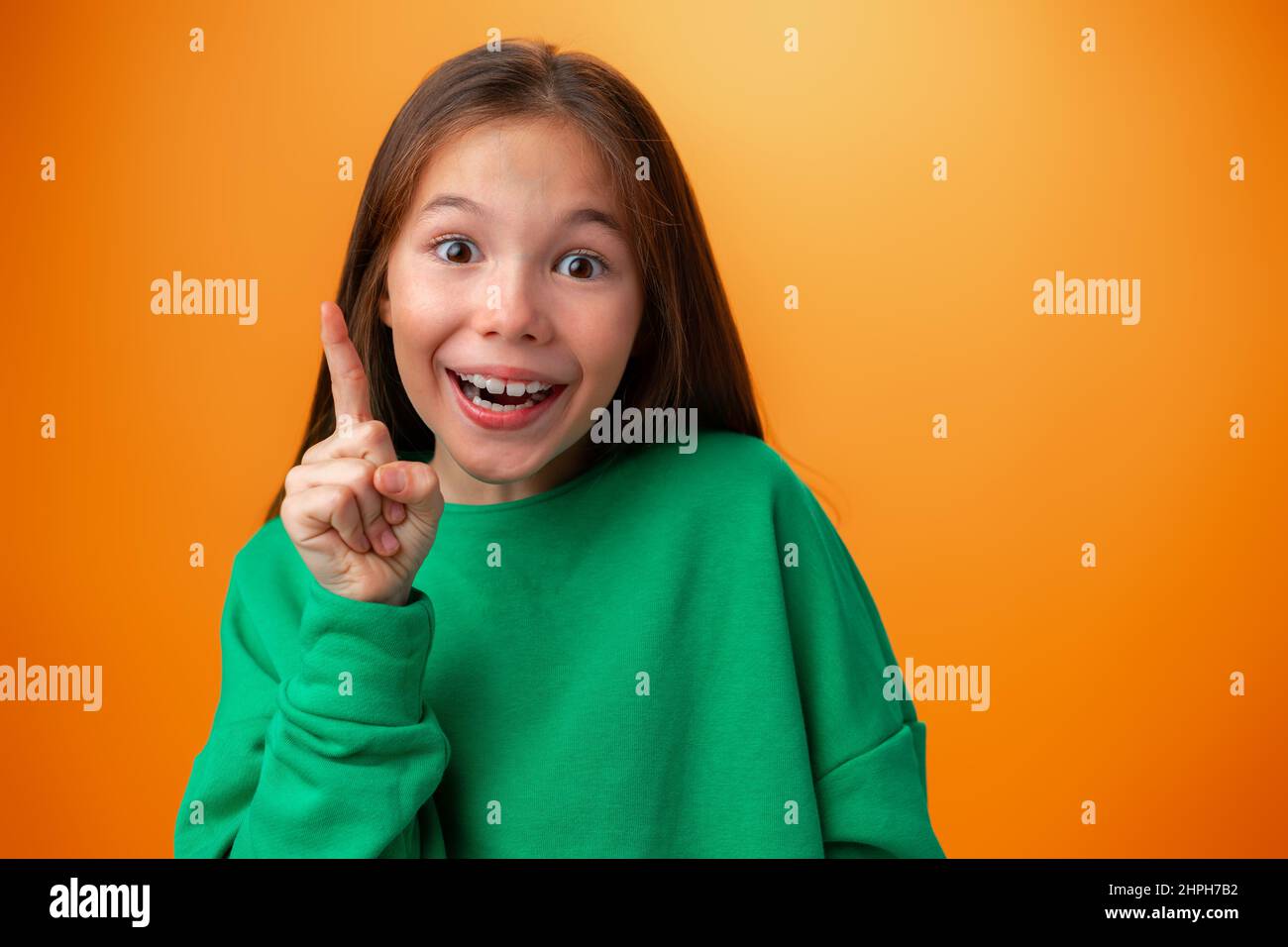 Portrait of cute thoughtful teen girl against orange background Stock ...