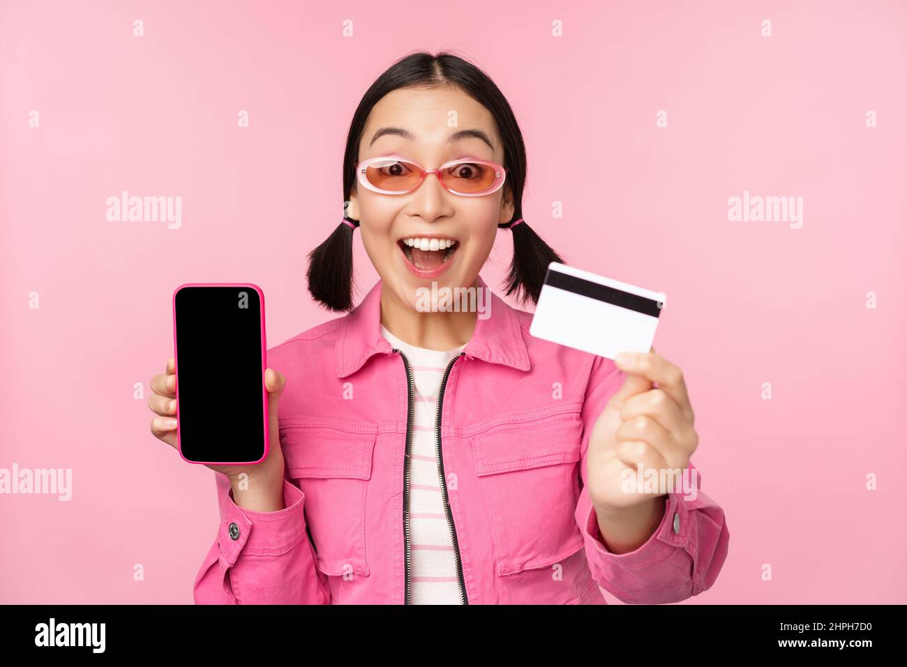 Asian girl shows mobile phone screen and credit card, reacts surprised ...