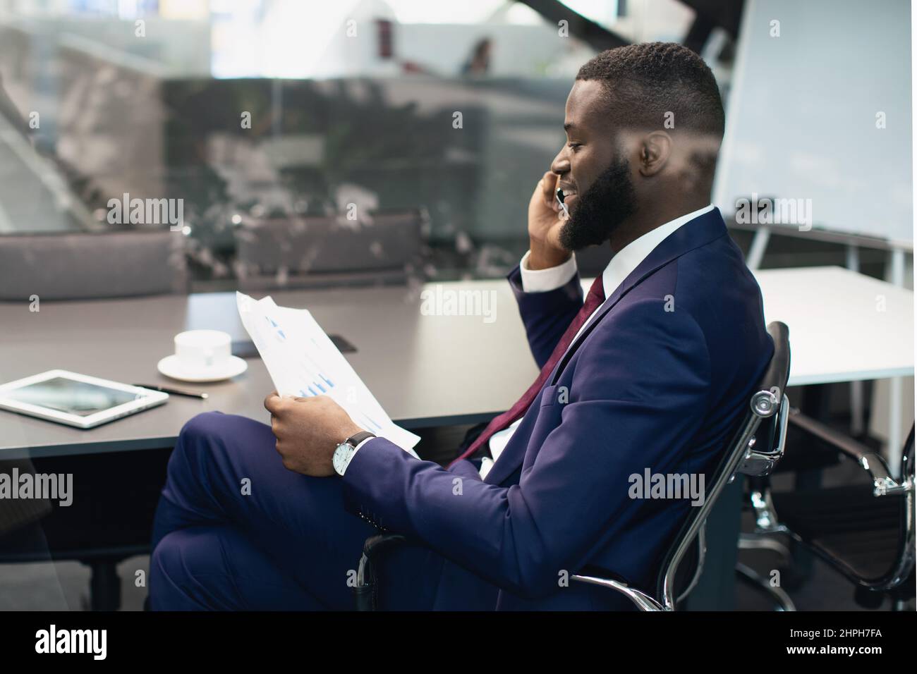 African american manager having phone conversation, reading papers ...