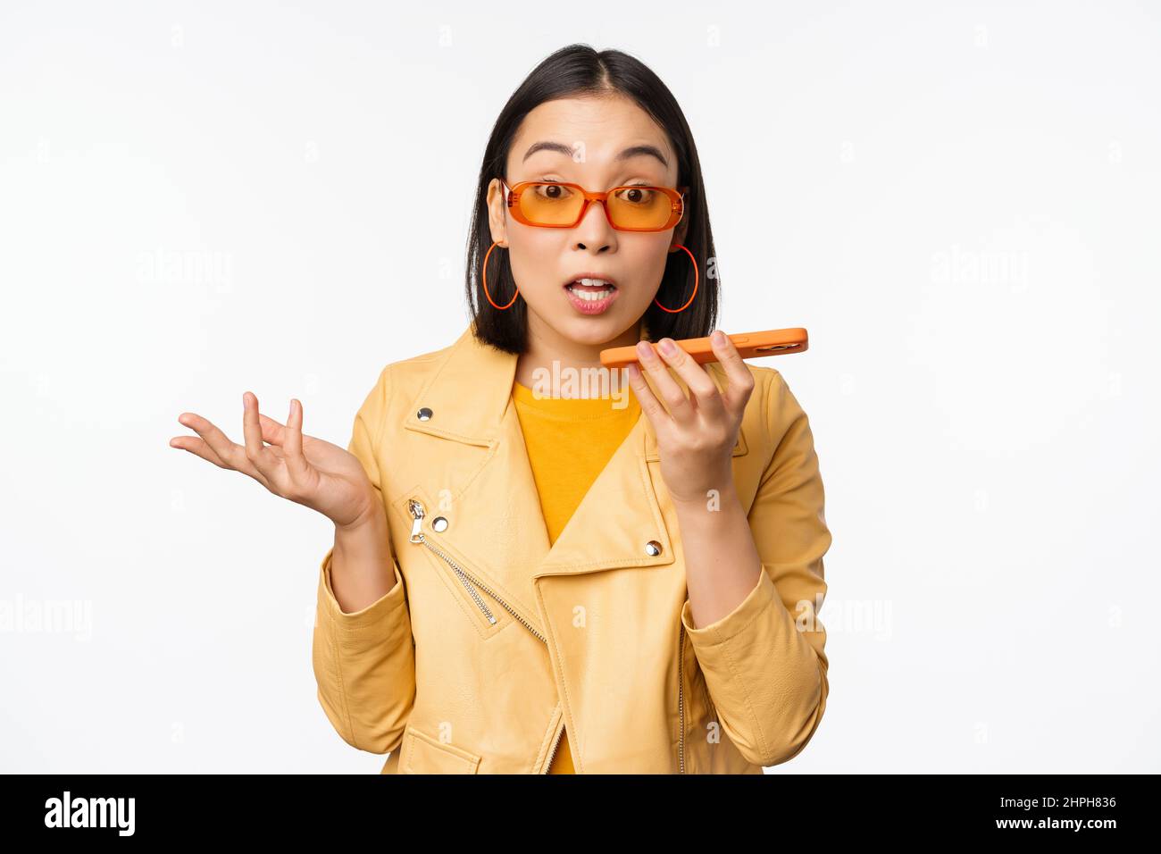 Image of happy asian girl talking on speakerphone, recording ...