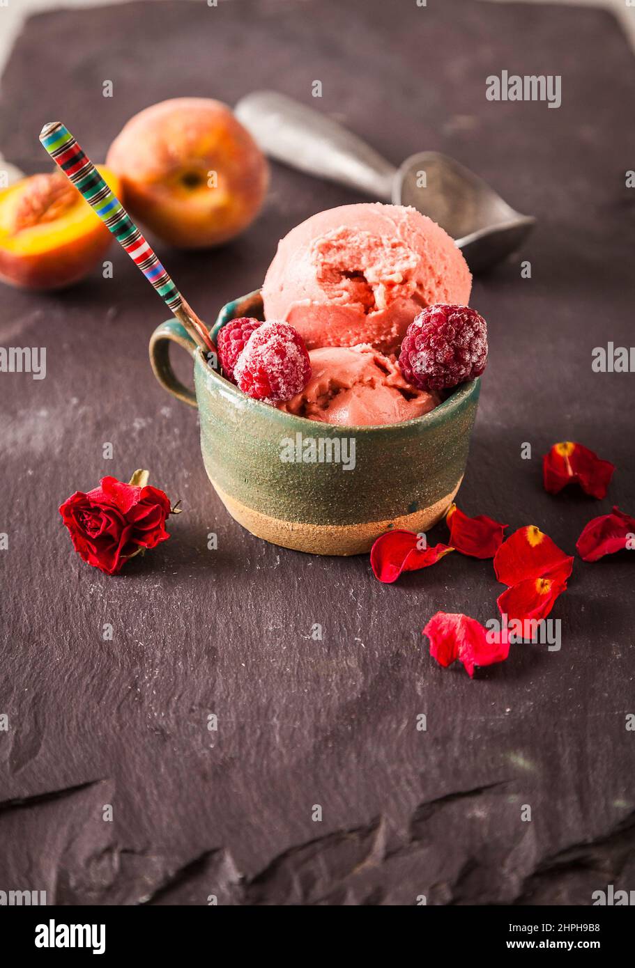 Italian style ice cream (gelato) in a cup with fruit on a slate ...