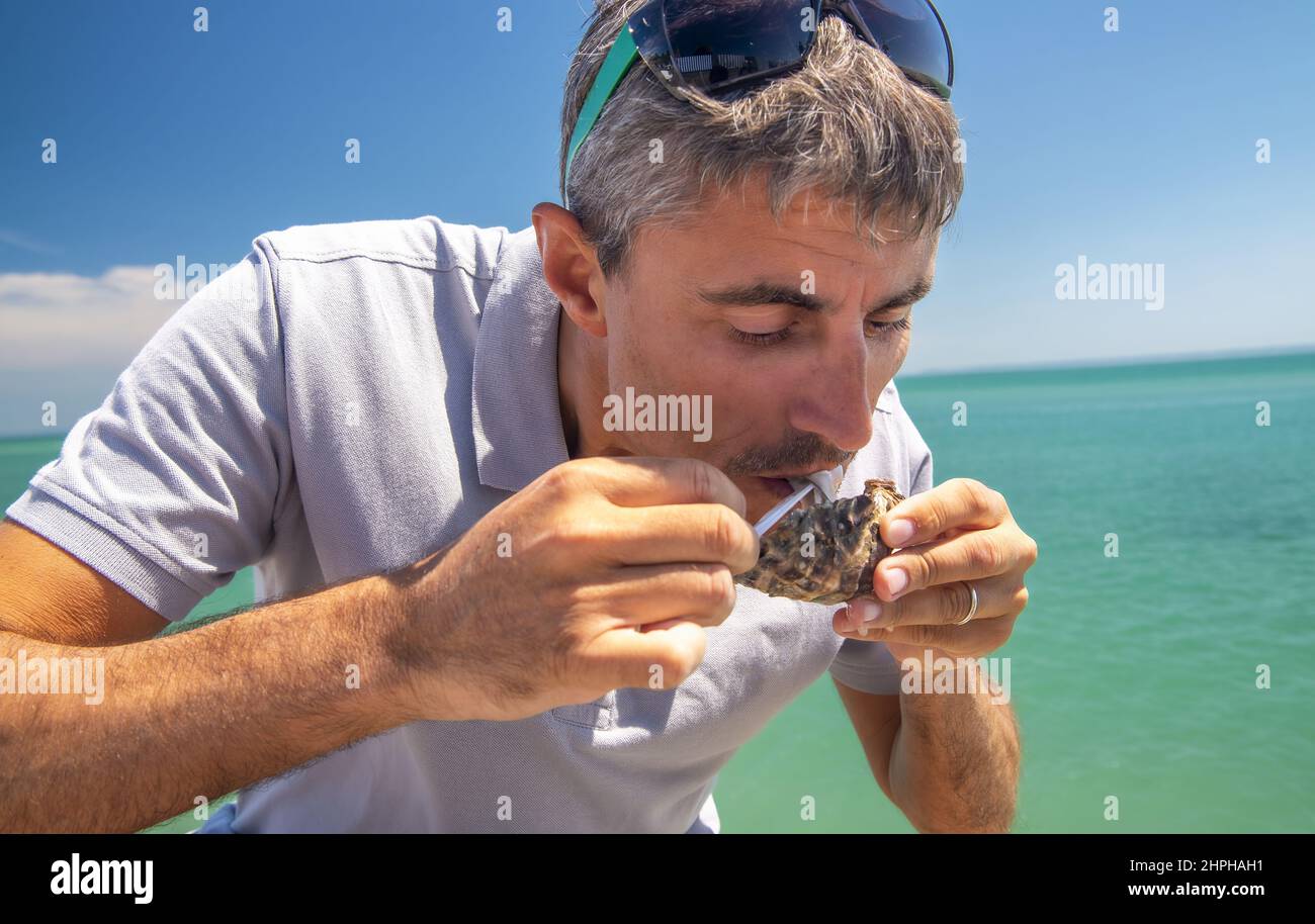Man eating a fresh oyster outdoor along the ocean Stock Photo - Alamy