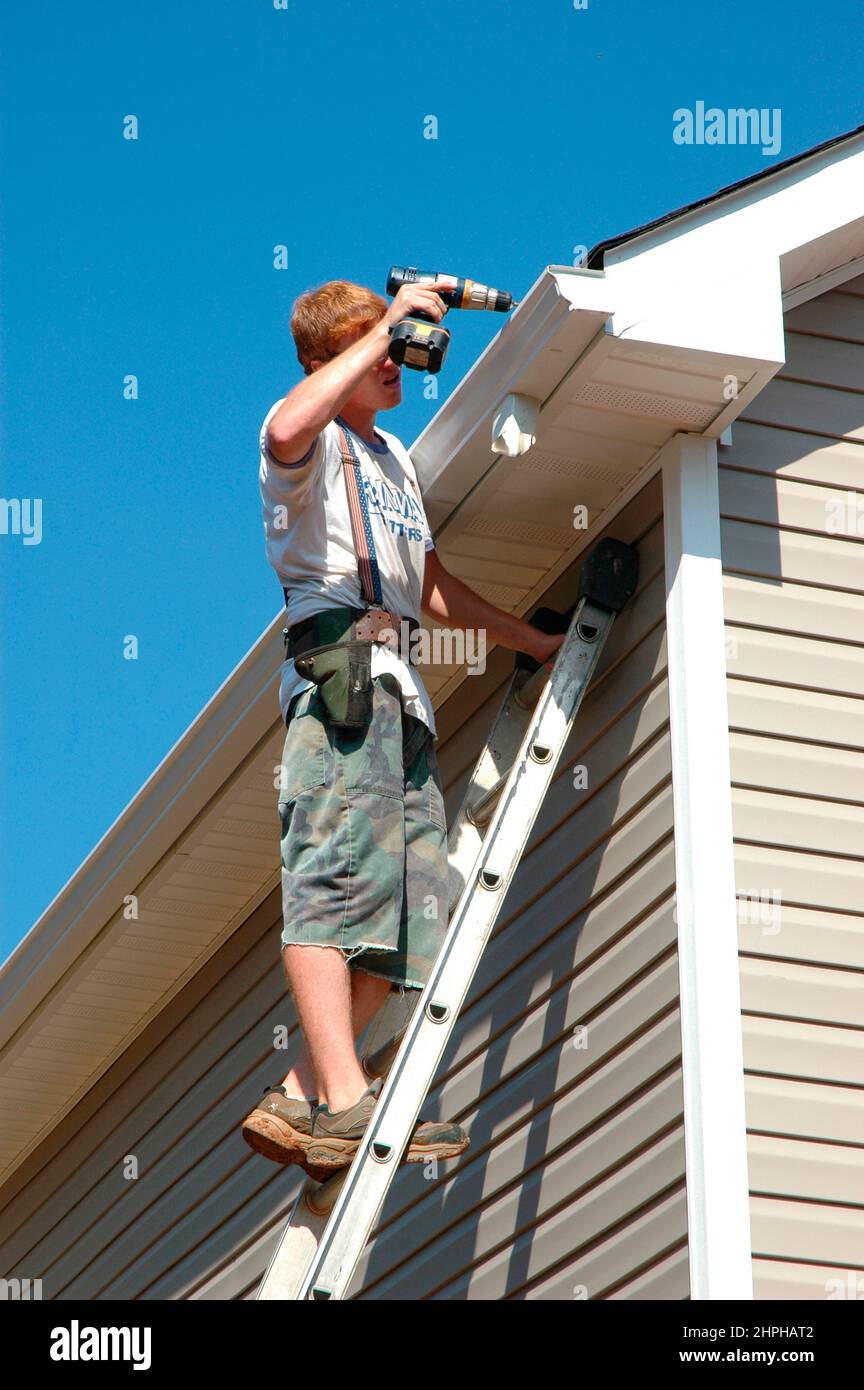 Installation of rain water run off gutters by young men on ladders and ...