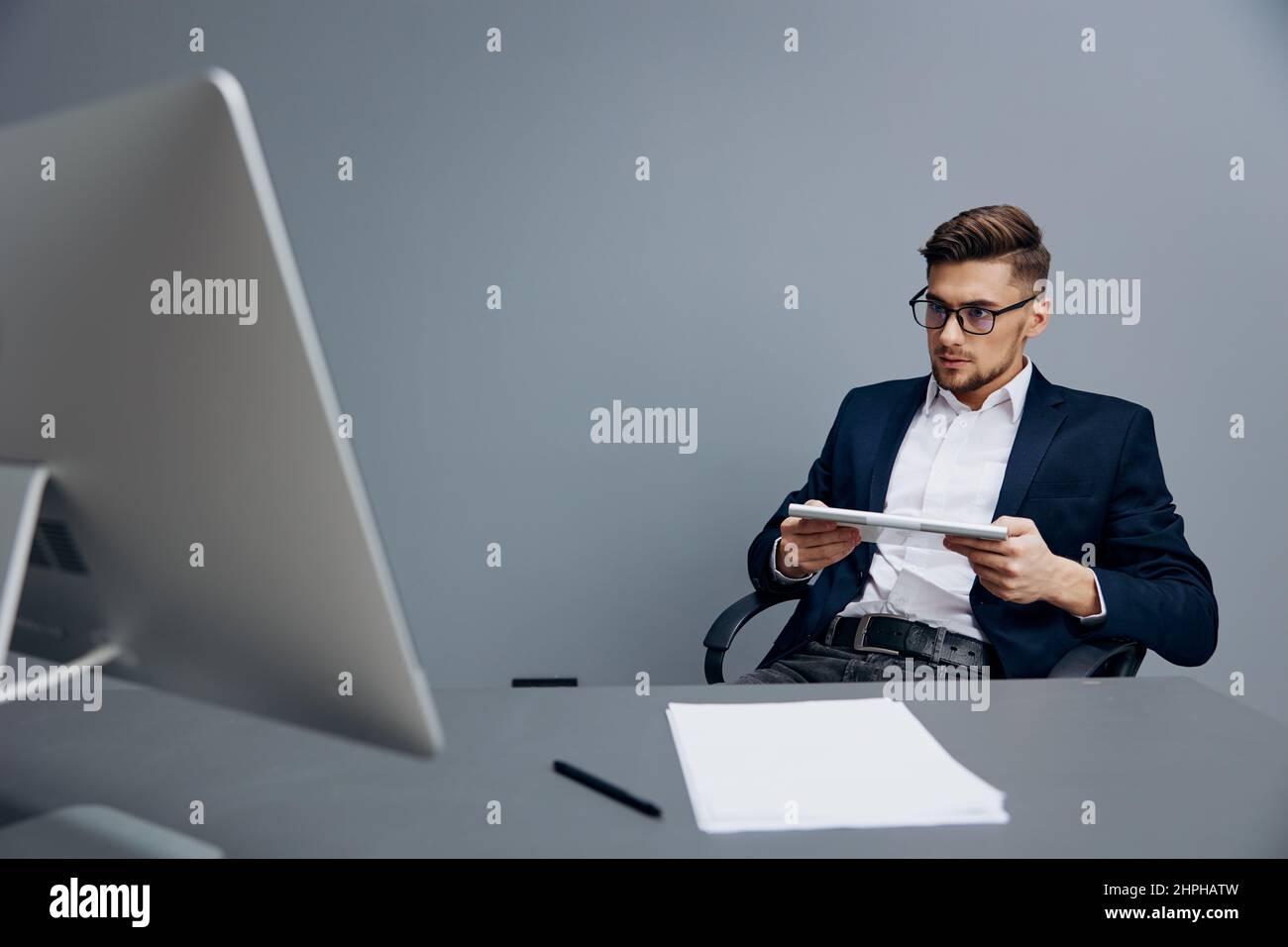 manager sitting at a desk in front of a computer Gray background Stock ...