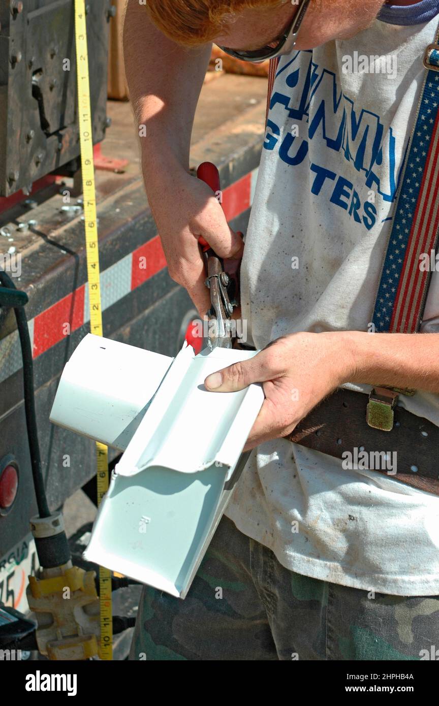 Installation of rain water run off gutters by young men on ladders and ...