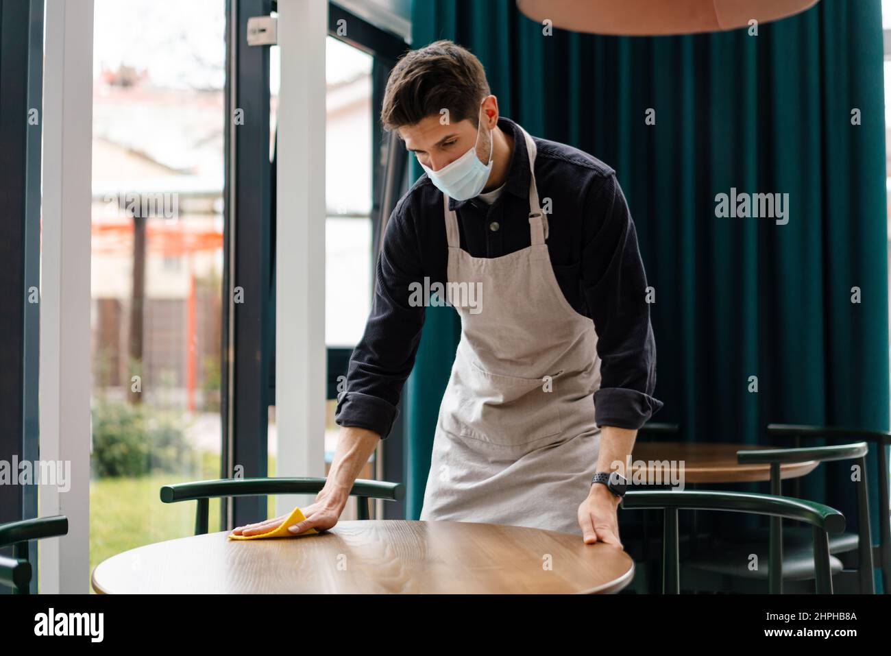 Man waiter wearing mask disinfecting table in the cafe indoors Stock ...