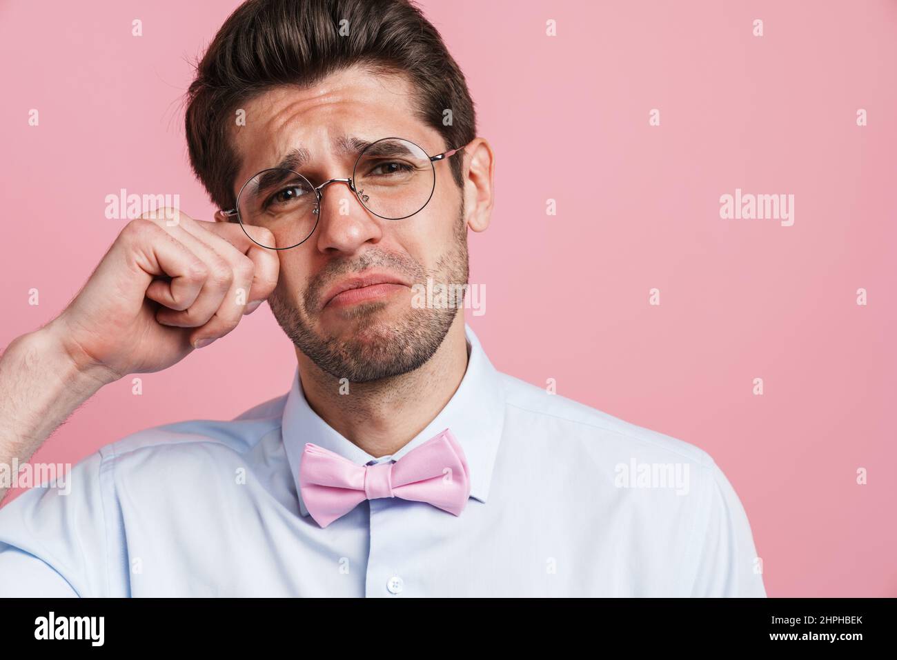 Young white man wearing bow tie crying and wiping his tears isolated ...