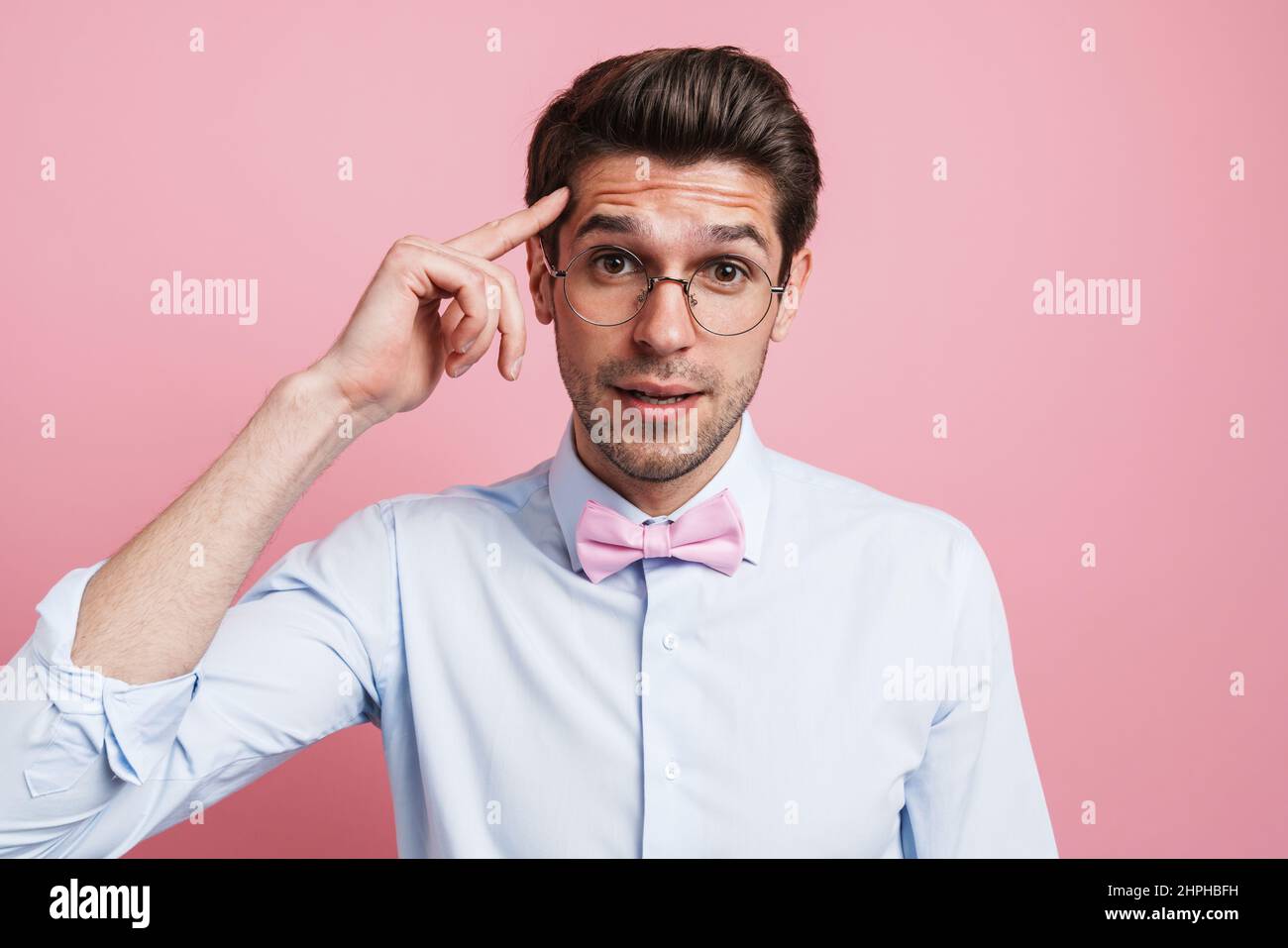 Portrait of a confused frowning young brunette nerd man wearing shirt ...