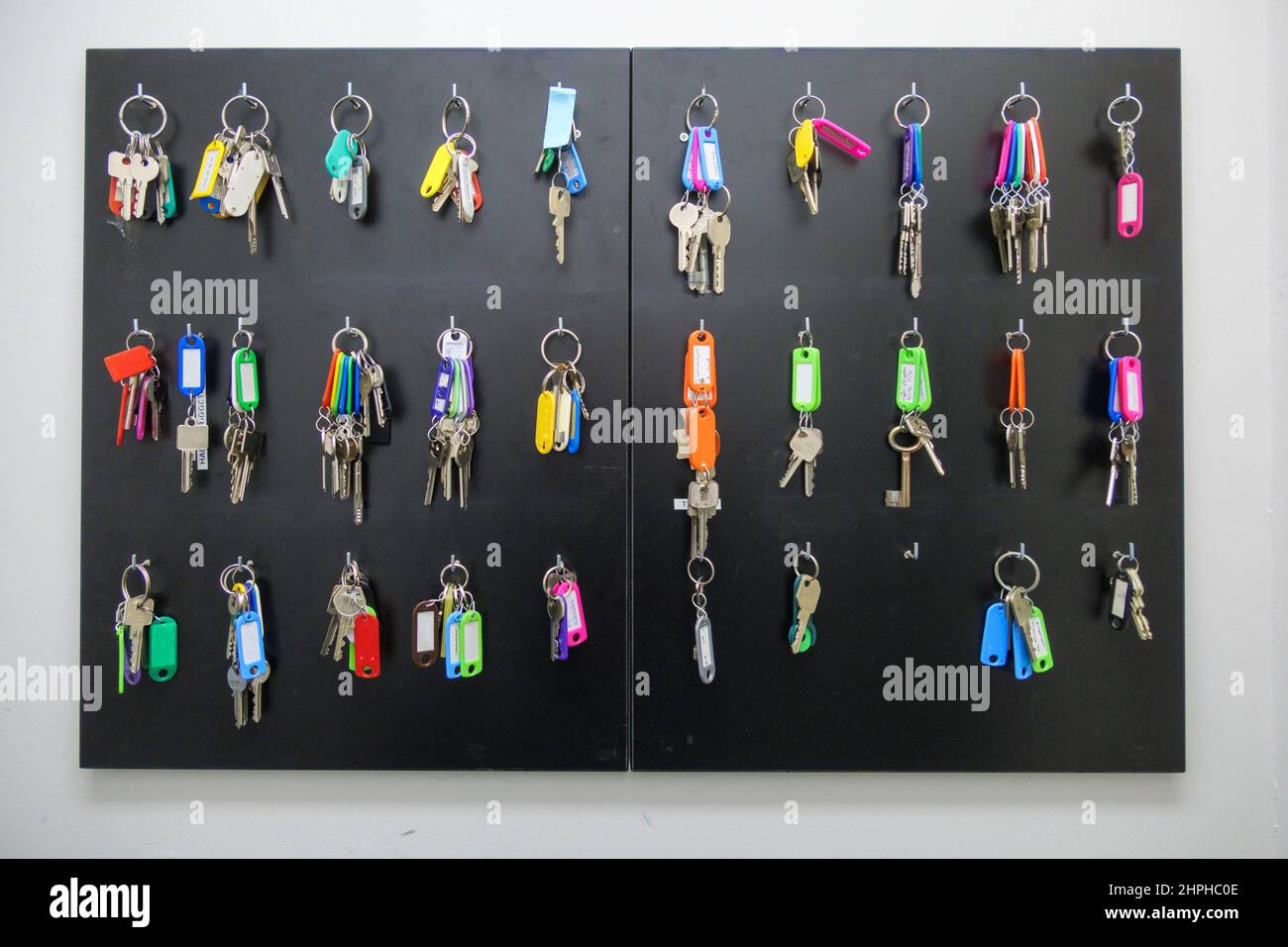 on a black key board hang many different keys with colorful key chains ...