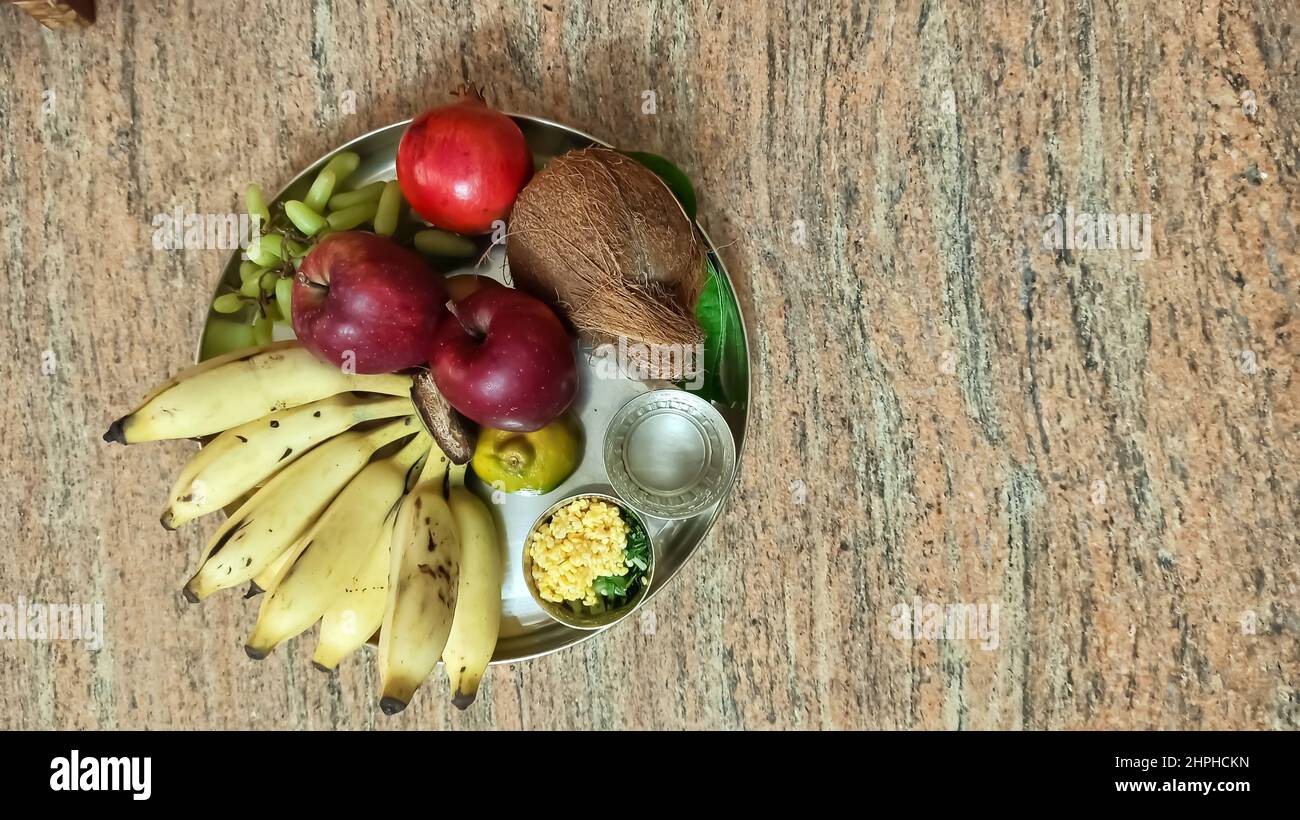 A closeup picture of various fruits in a silver plate on a granite ...