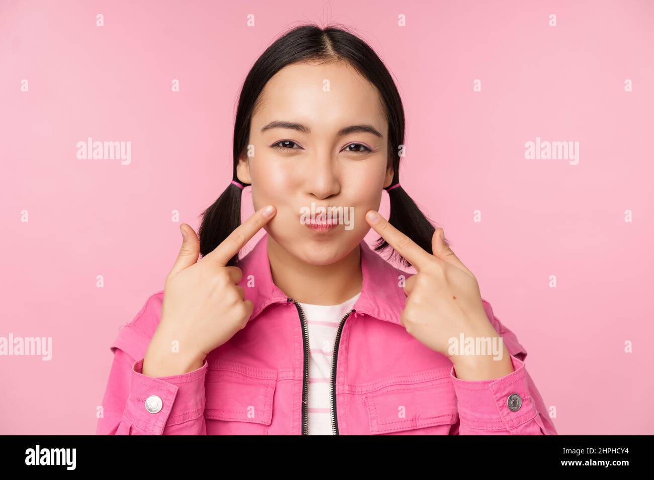 Close up portrait of young asian girl showing her dimples, poking ...