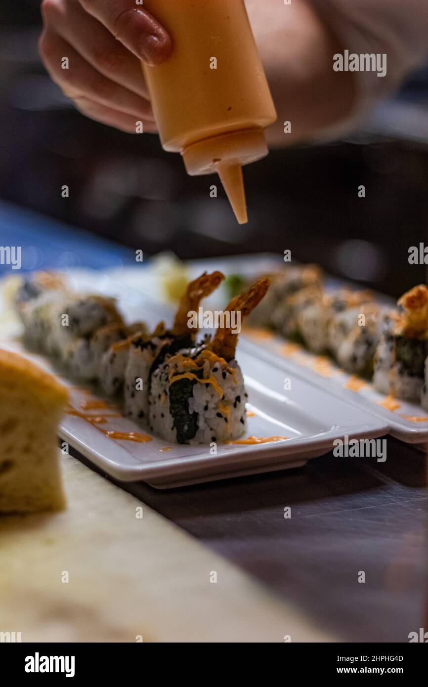Dynamite sushi rolls being prepared in restaurant kitchen rsetting on ...
