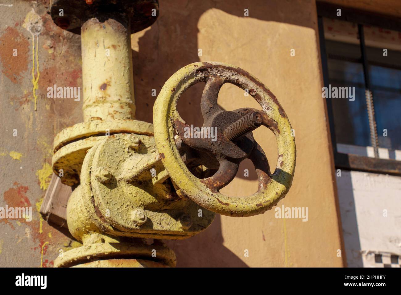 Old rusty gas control valve on the wall. An industrial valve in a large ...
