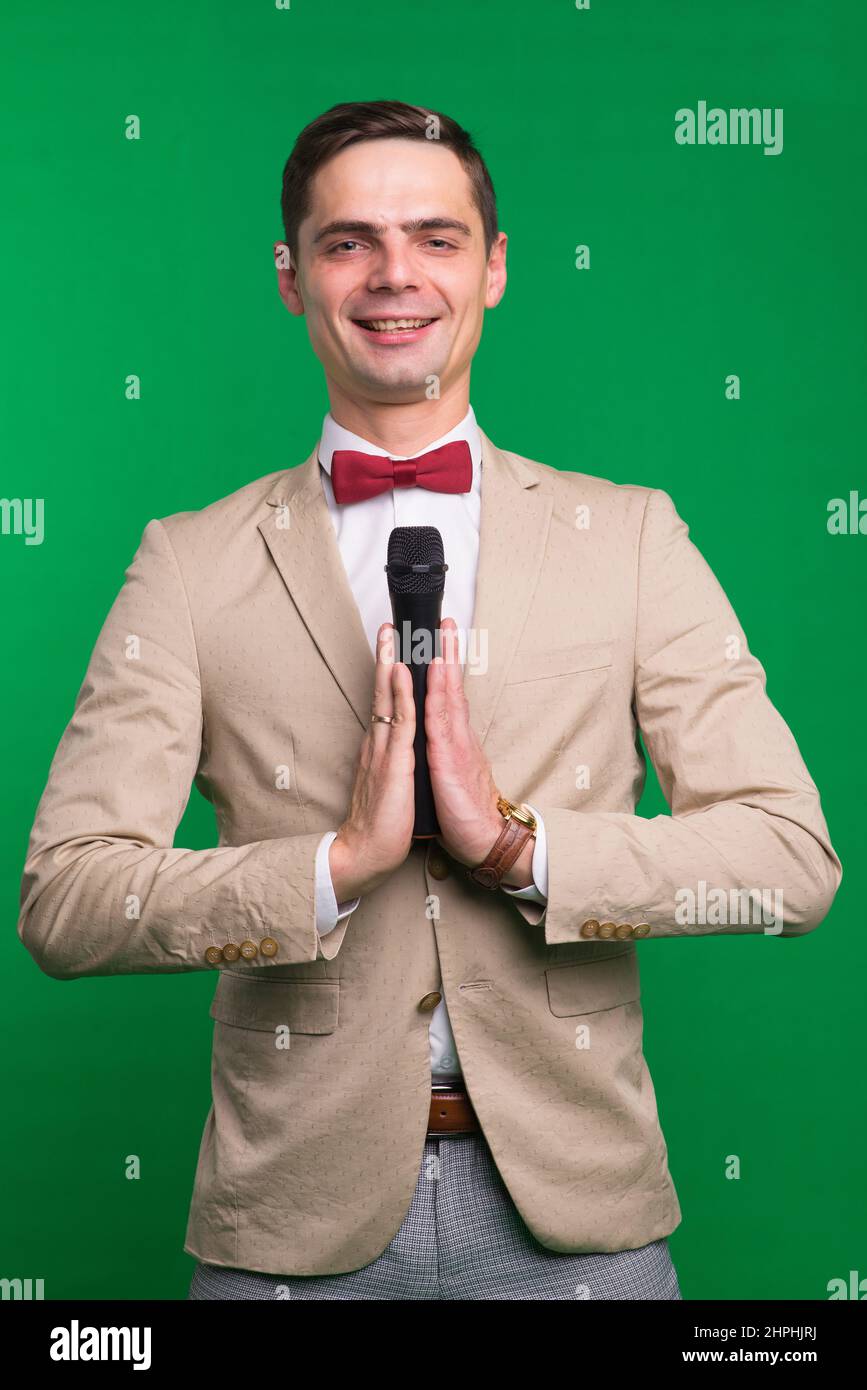 Portrait of male announcer holding microphone, isolated on green, white ...