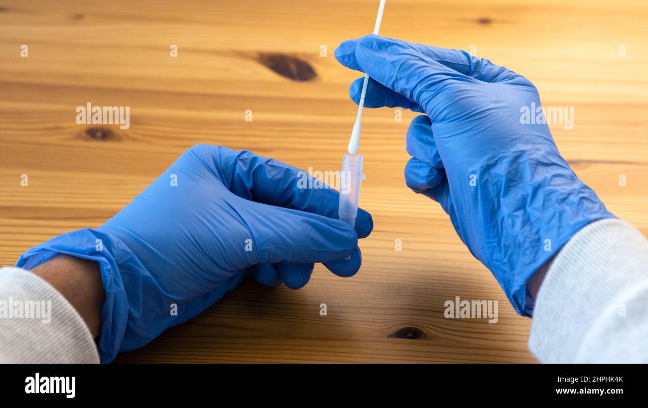 Close-up of man wearing latex gloves taking a self swabbing home tests ...