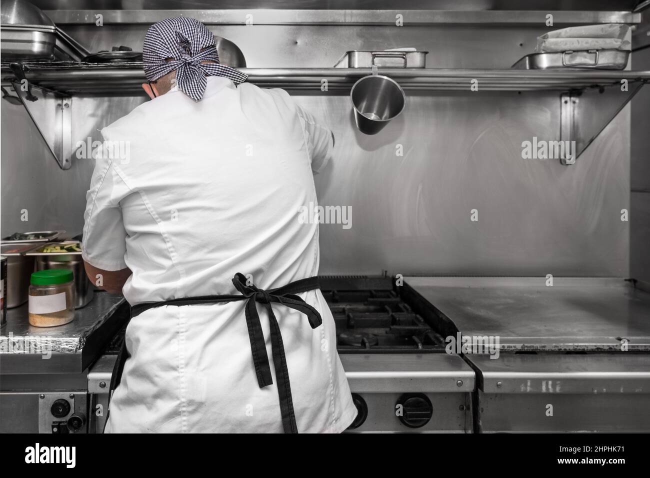 Back view of woman chef cooking food in the kitchen of a restaurant ...