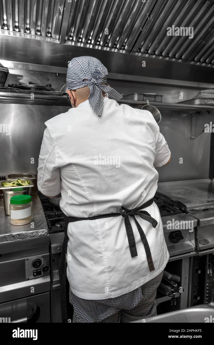 Back view of woman chef cooking food in the kitchen of a restaurant ...