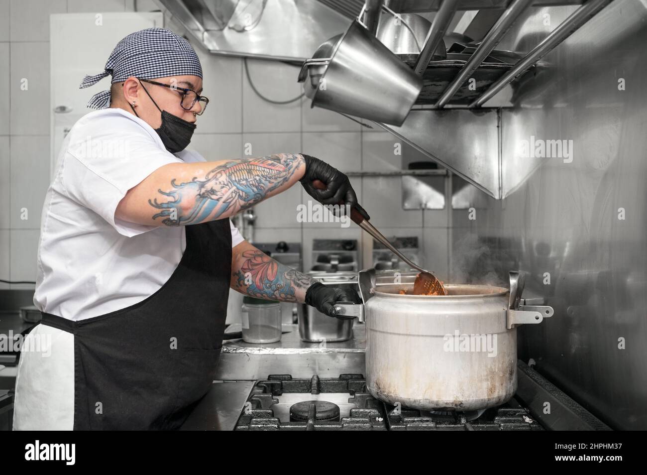 Side view of female chef working in commercial kitchen. High quality ...