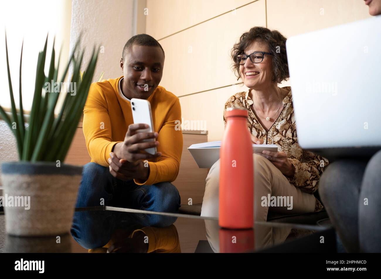 Black man showing something funny on his cell phone to his colleague ...