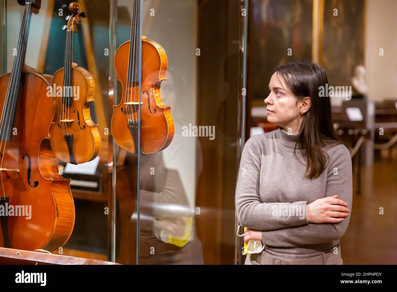 Interested brunette visiting exhibition of medieval musical instruments ...
