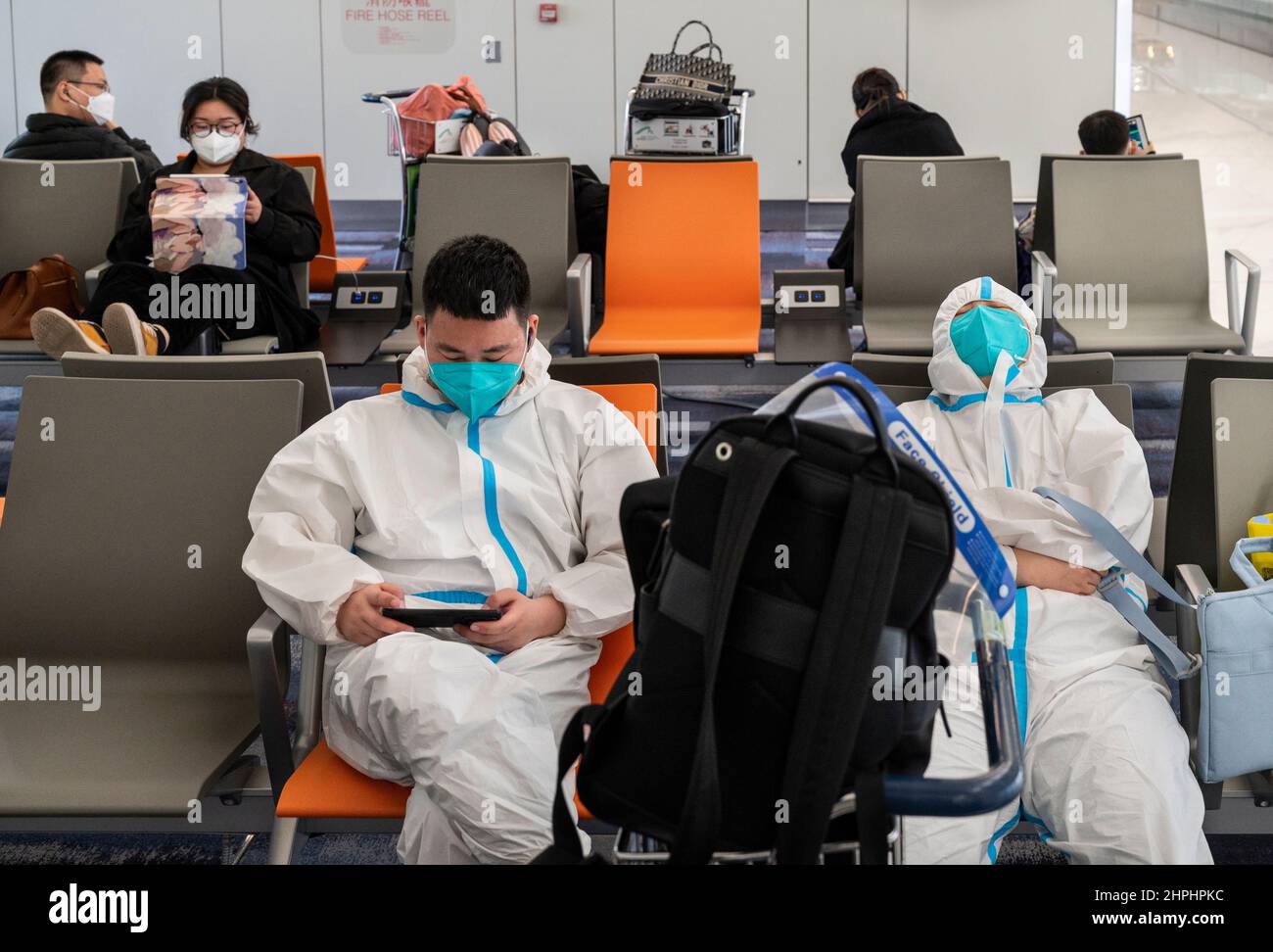Passengers wearing personal protective equipment (PPE) wait to board ...