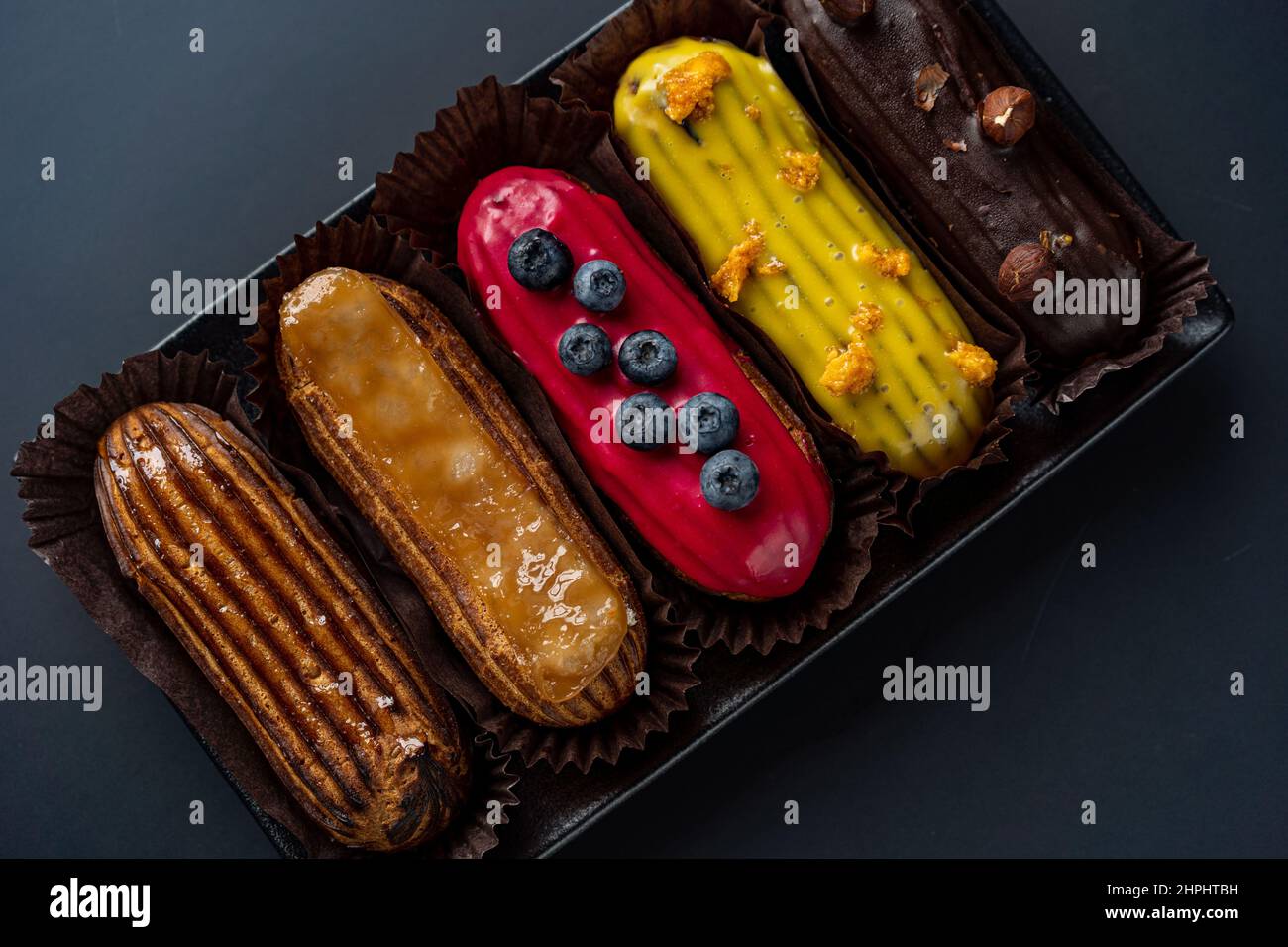 colorful eclairs on a black plate on a black background top view Stock ...