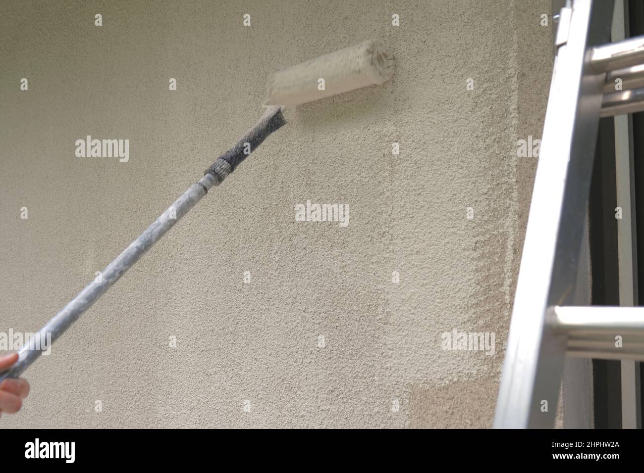 painting roller and metal building ladder on a beige wall.Home ...