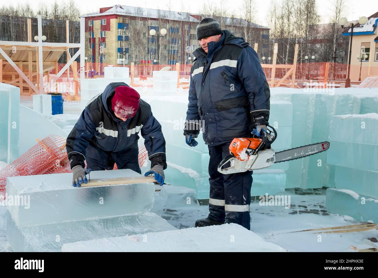 Workers installers mark the ice block on the territory of the ice town ...