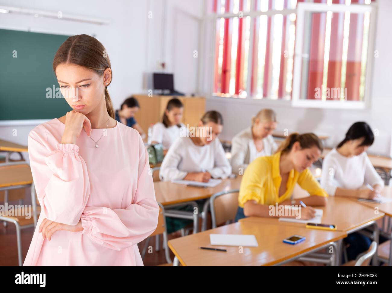 Upset female student standing in classroom Stock Photo - Alamy