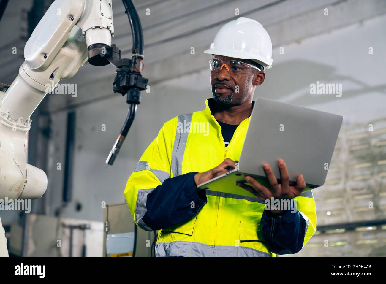 African American factory worker working with adept robotic arm in a ...