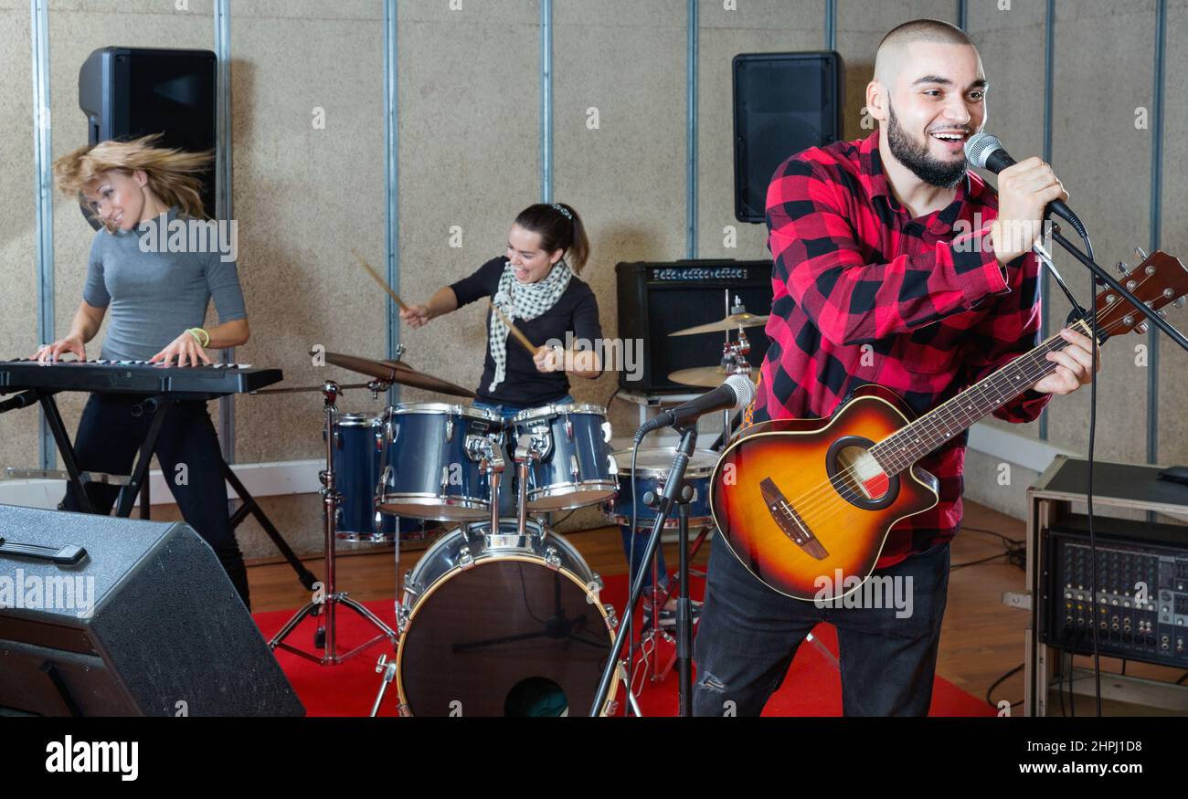 Guy guitar player and singer practicing with band members in recording ...