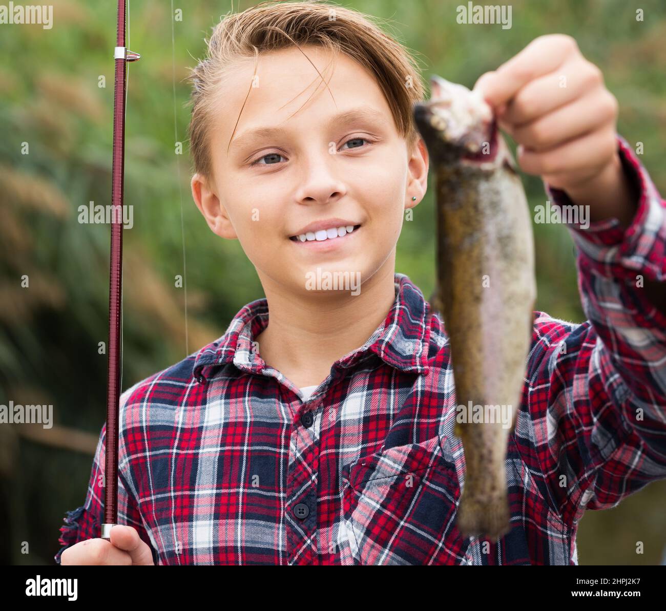 Positive teenage boy holding catch fish in hands Stock Photo - Alamy