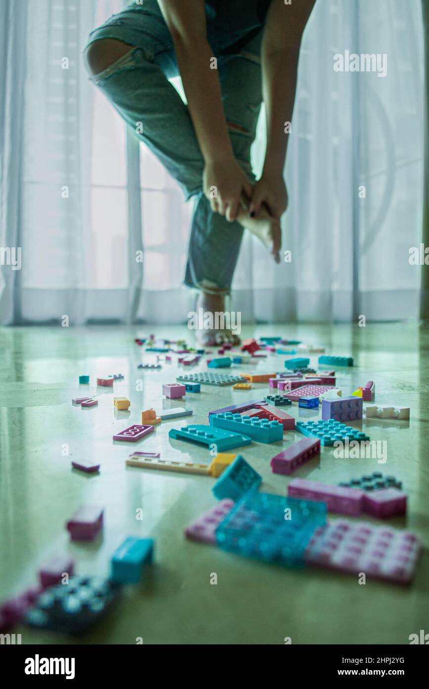 Human standing holding his leg with game colorful cubes on the ground ...