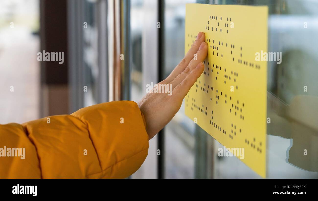 Close-up of a woman reading a braille lettering on a glass door Stock ...