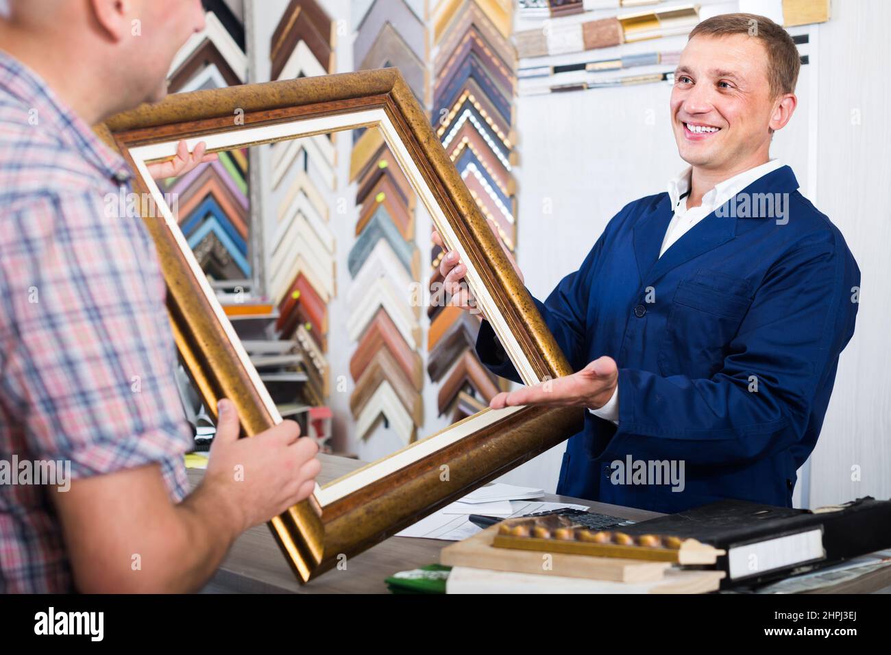 portrait of man seller taking order on picture frame from customer at ...