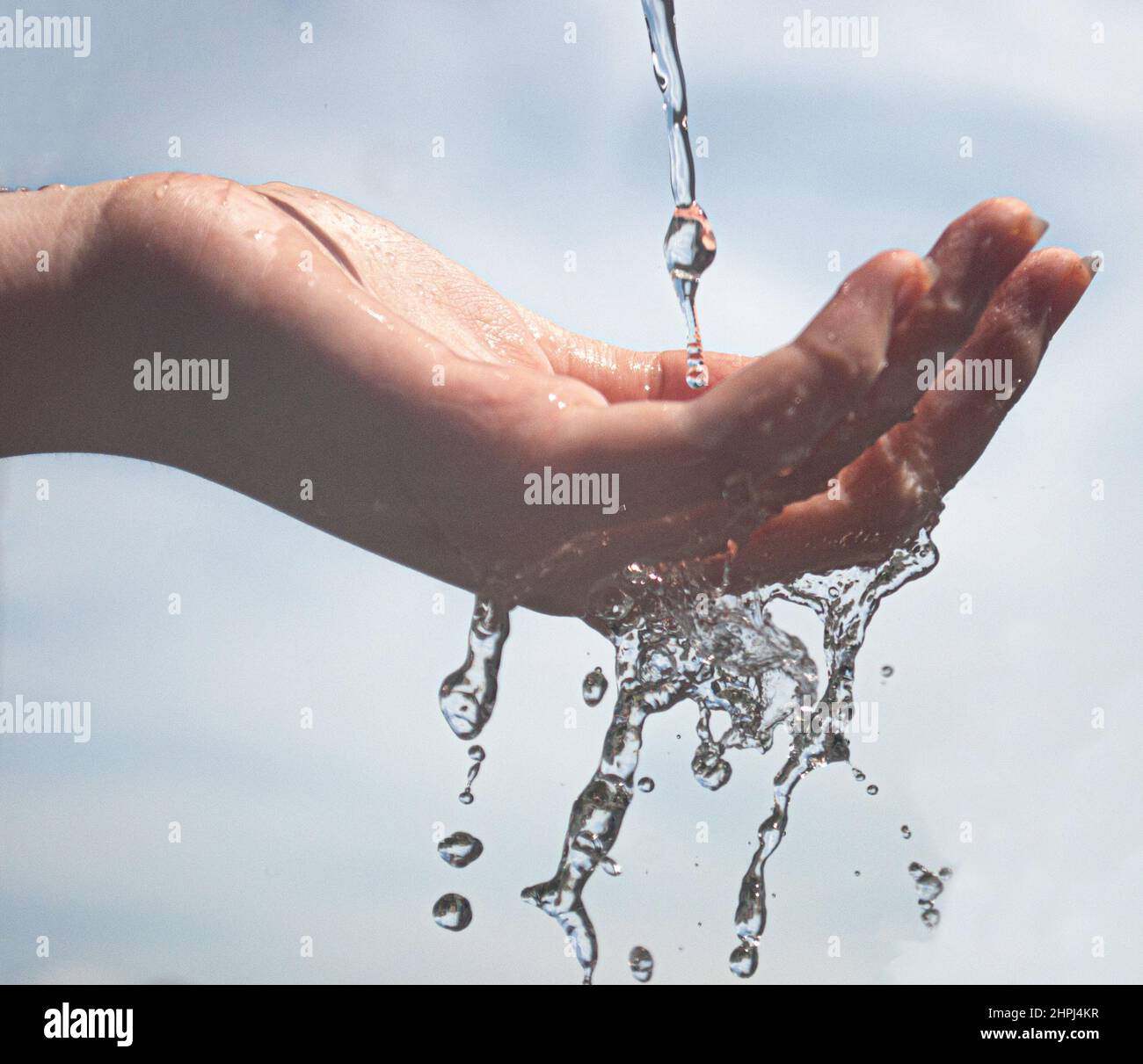 Closeup of water drops falling down through a human with a blurred blue ...