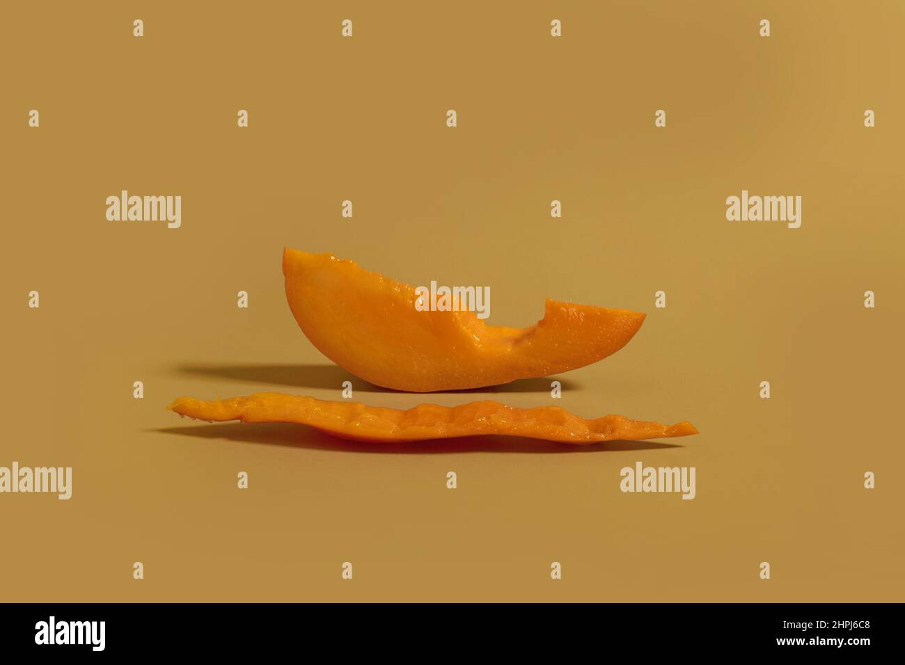 Bitten mango slice and eaten peel on a colored background Stock Photo ...