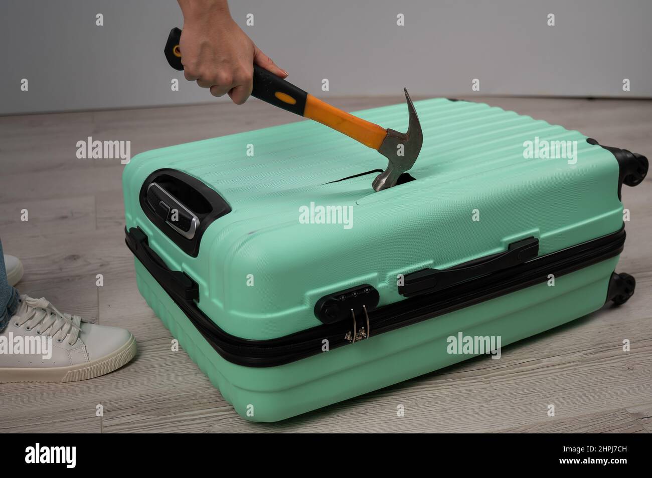A woman hits a suitcase with a hammer on a white background Stock Photo ...