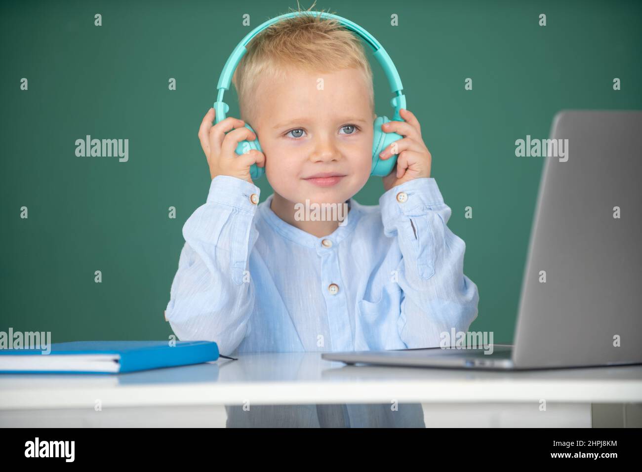 Cute boy wearing headphones, study with laptop in classroom, listening ...