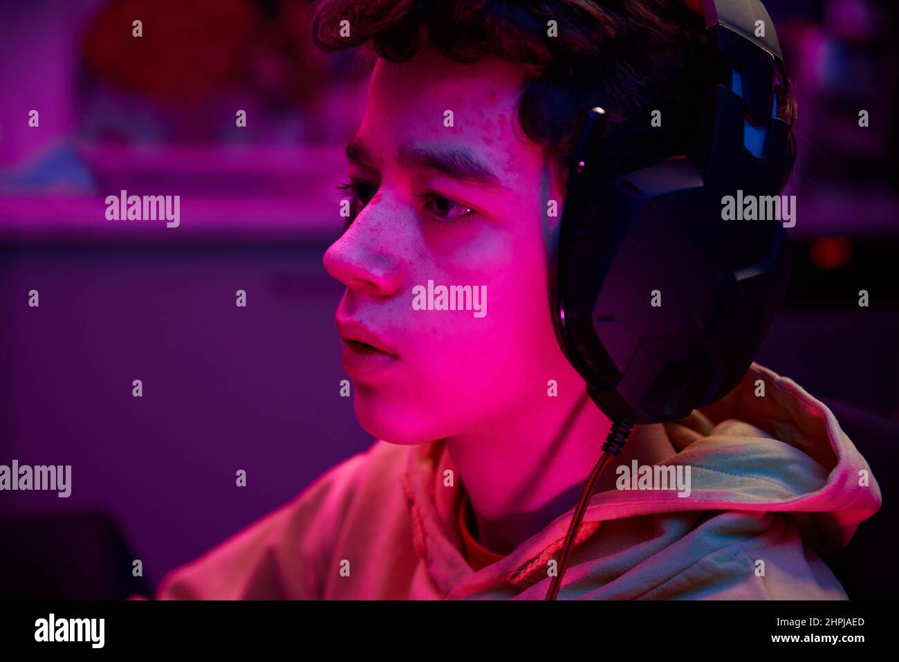 Portrait of teenager boy playing computer video game in dark room ...