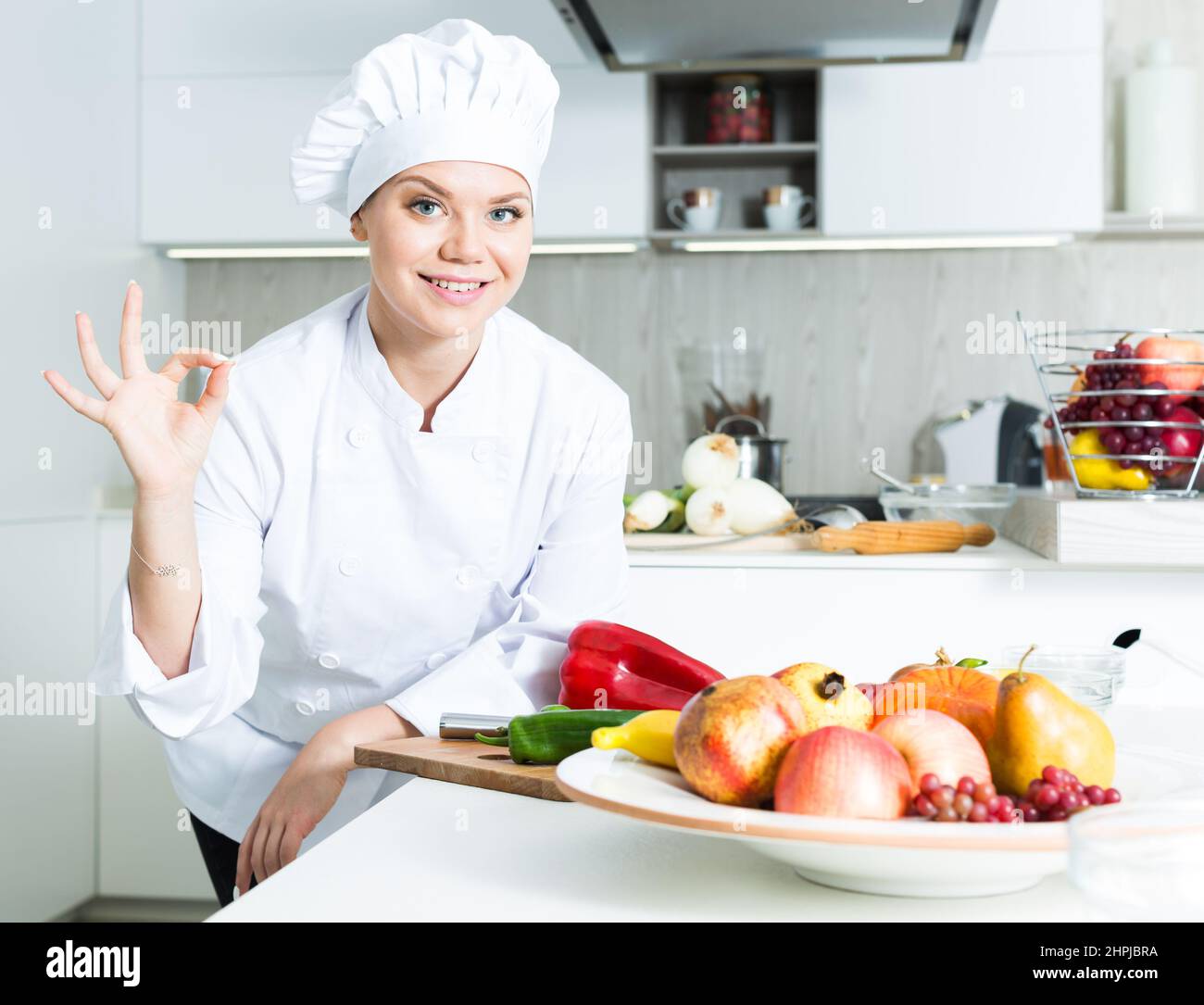 Female cook in uniform showing ok hand sign on kitchen Stock Photo - Alamy