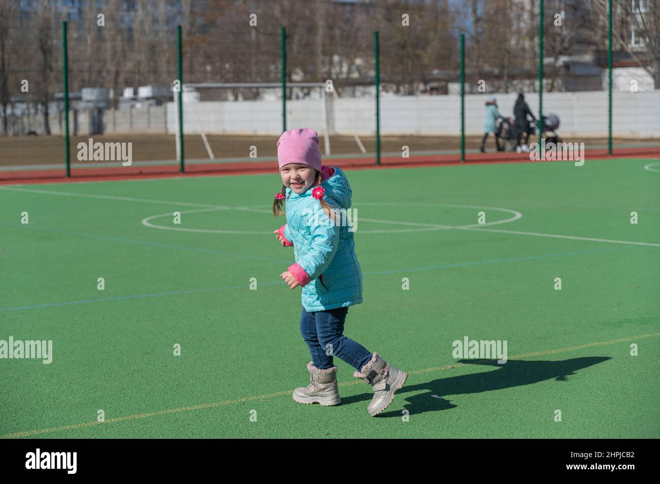 A happy child running around a green sports soccer field. A mischievous ...