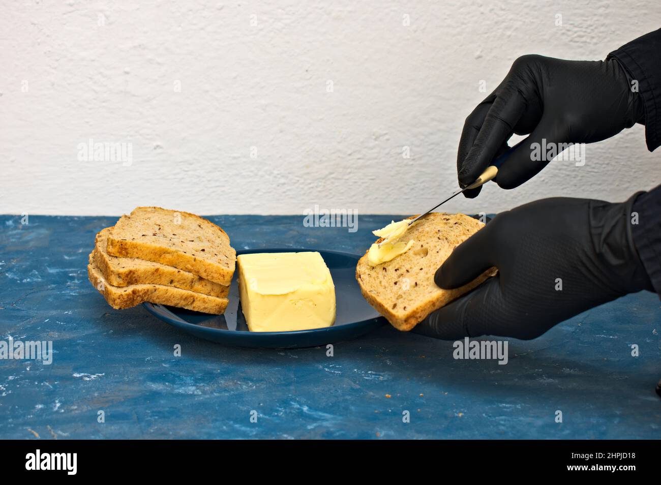 chef in gloves spreads butter with a knife on a slice of bread Stock ...
