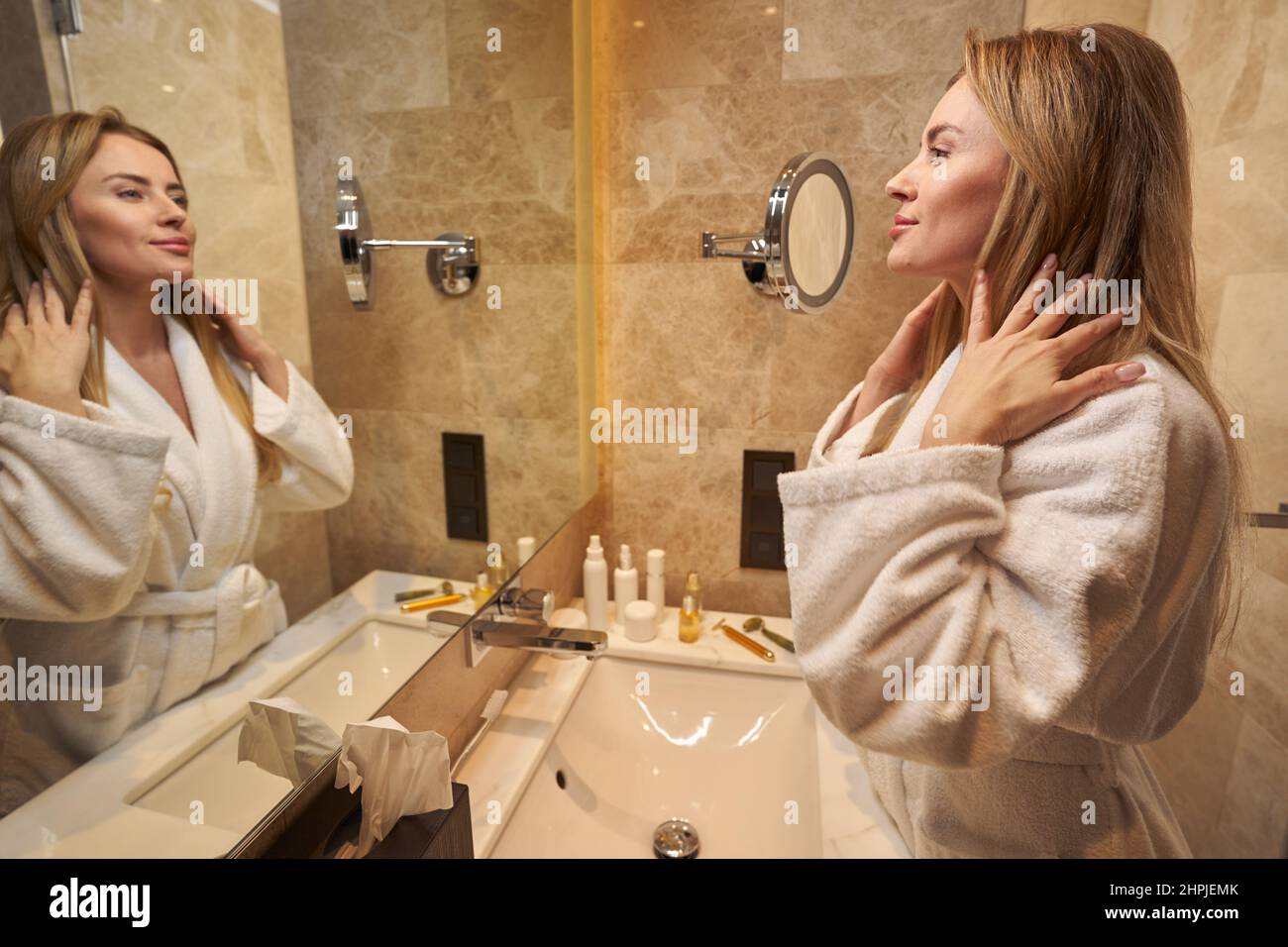 Contented lady admiring herself in bathroom mirror Stock Photo - Alamy